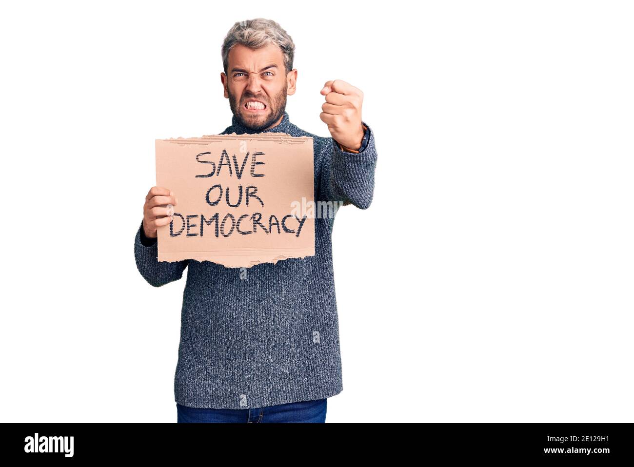 Young blond man holding save our democracy cardboard banner annoyed and ...