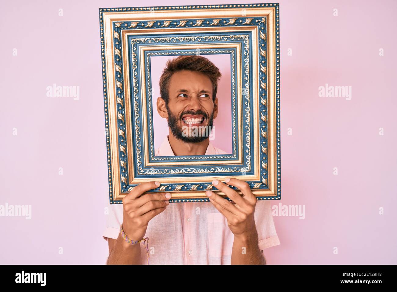 Handsome caucasian man with beard holding empty frame angry and mad ...