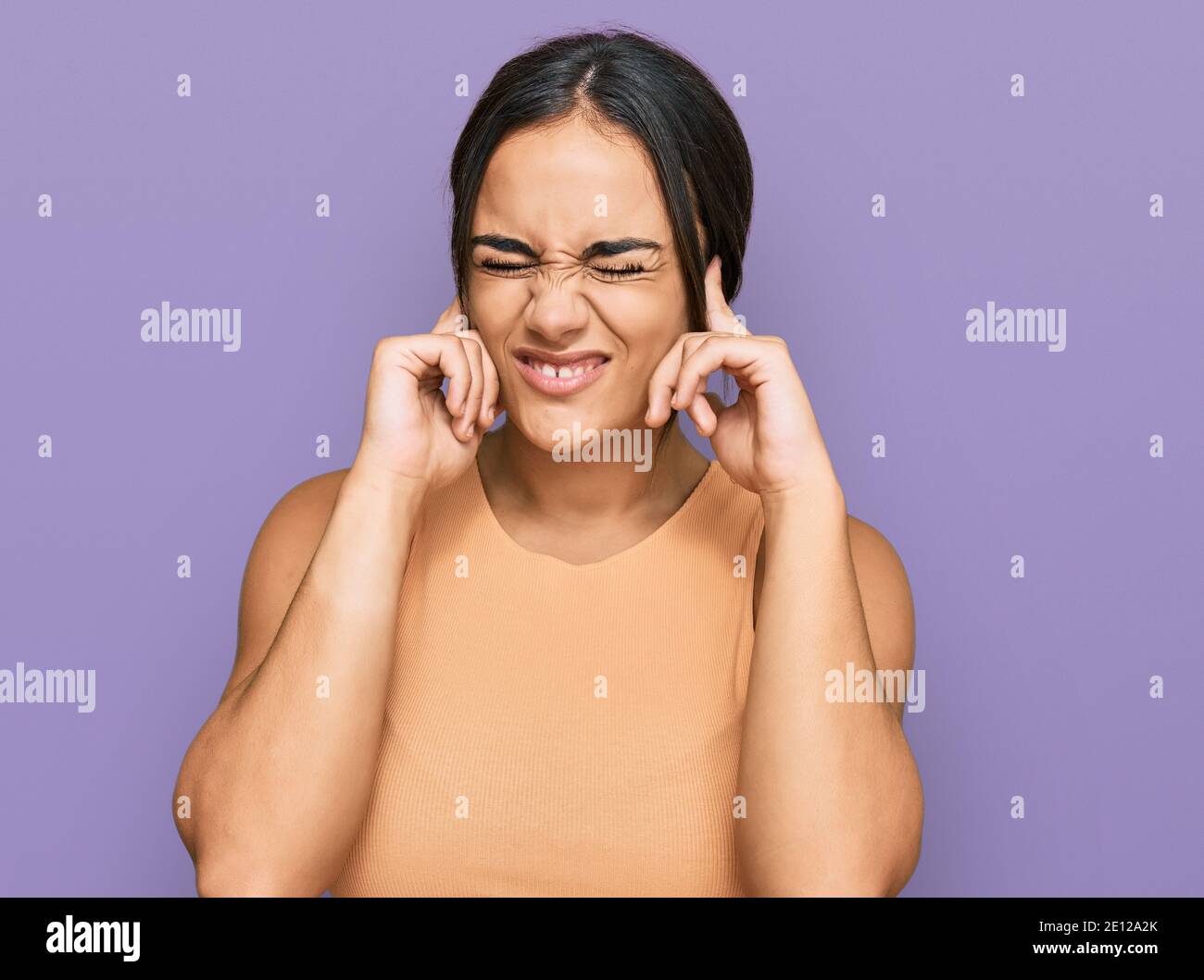 Young brunette woman wearing casual clothes covering ears with fingers ...