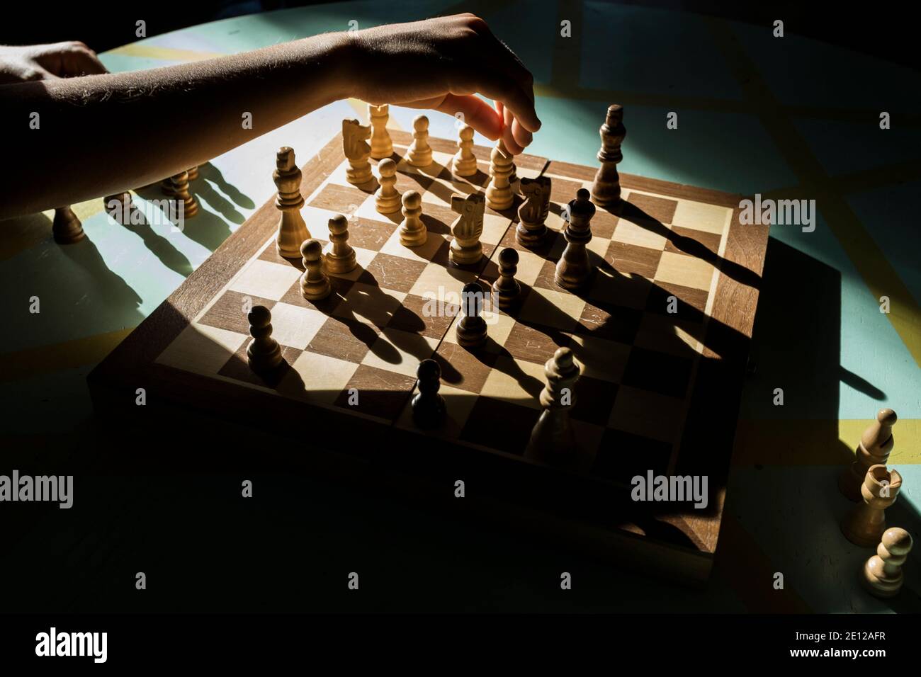 A close up view of a young girl's hand moving chess pieces in dramatic ...