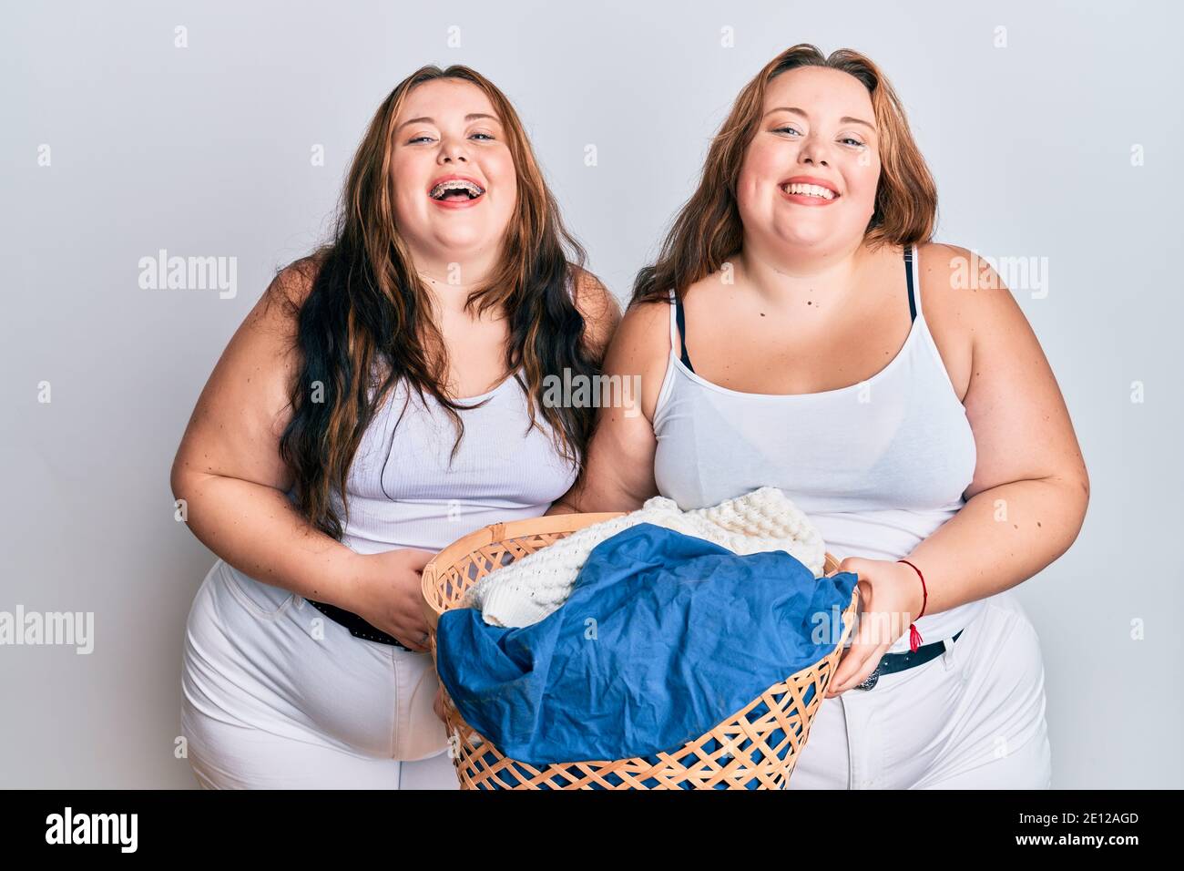 Plus size caucasian sisters woman holding laundry basket smiling and ...