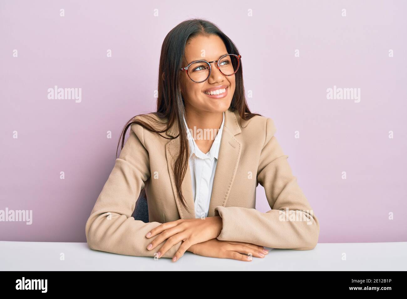 Beautiful hispanic woman working at the office looking away to side ...