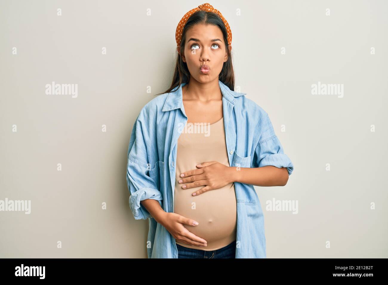 Beautiful hispanic woman expecting a baby, touching pregnant belly ...