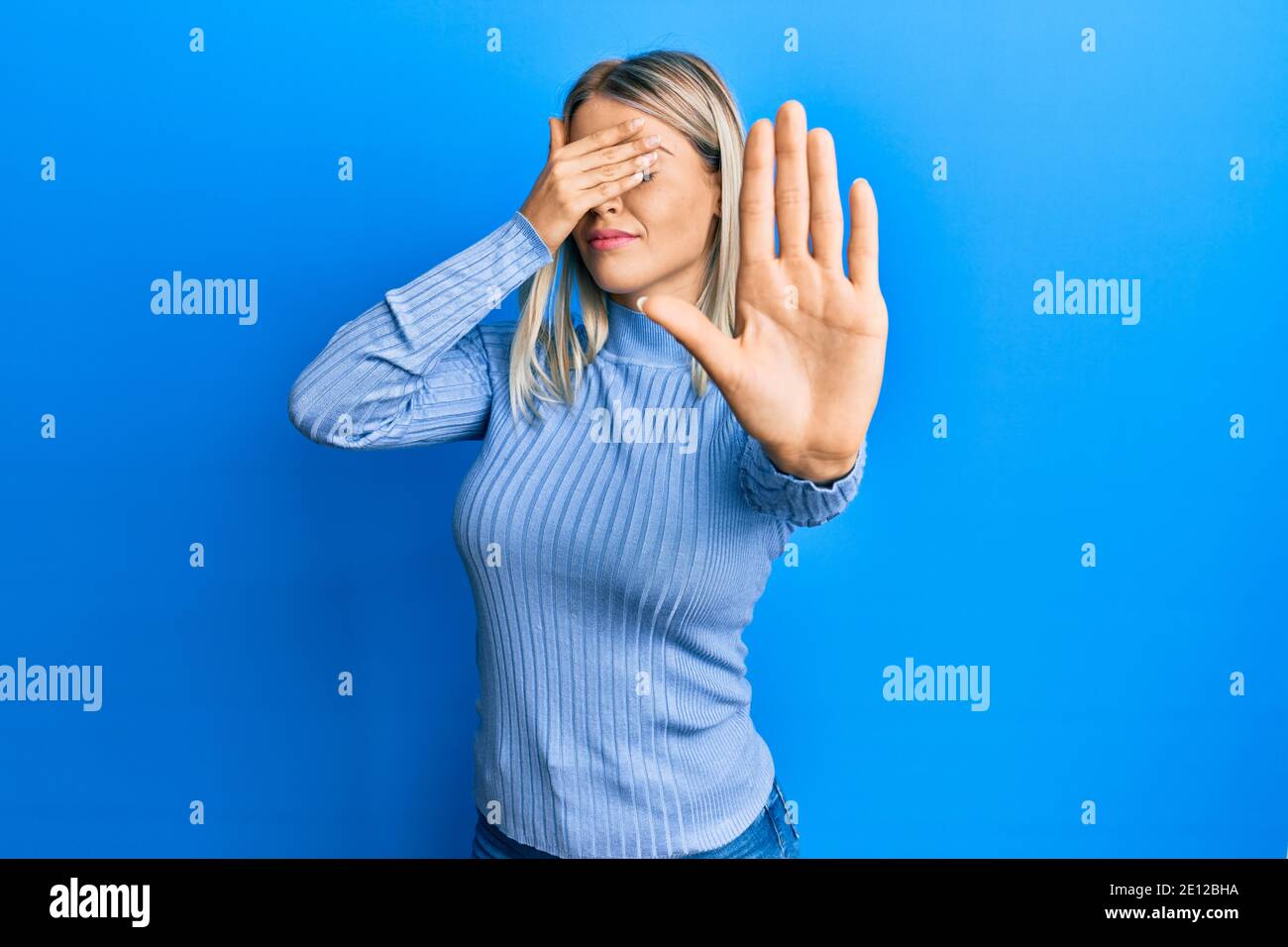 Beautiful blonde woman wearing casual clothes covering eyes with hands ...