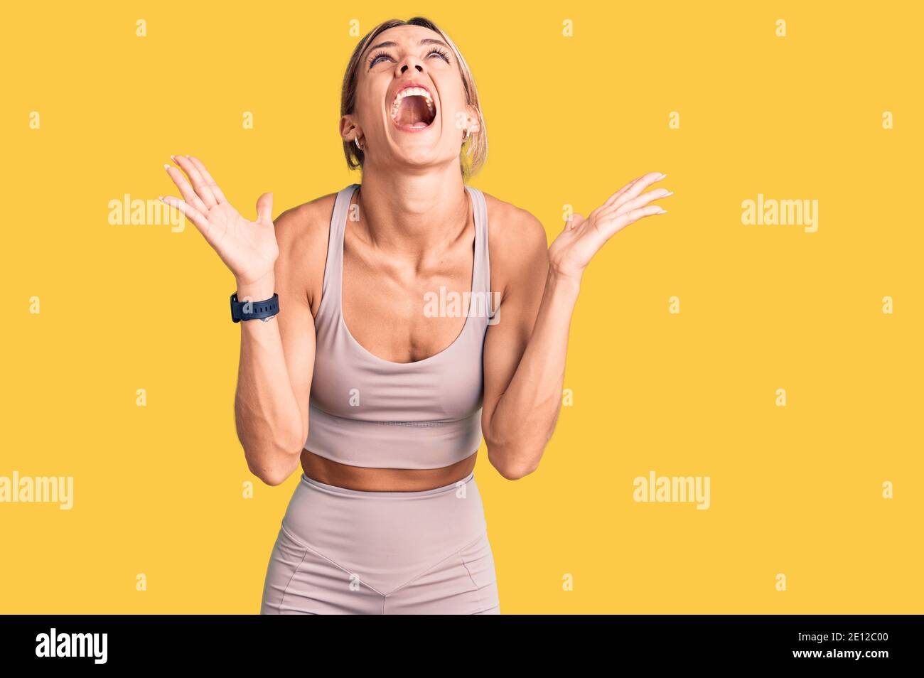 Beautiful caucasian woman wearing sportswear celebrating mad and crazy ...