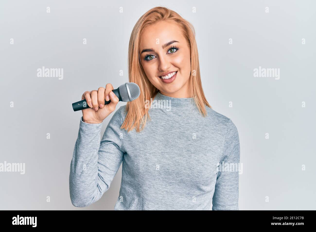 Beautiful caucasian woman singing song using microphone looking ...