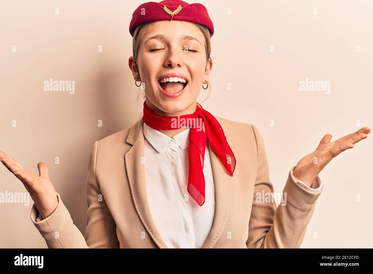 Young beautiful blonde girl wearing stewardess uniform celebrating mad ...