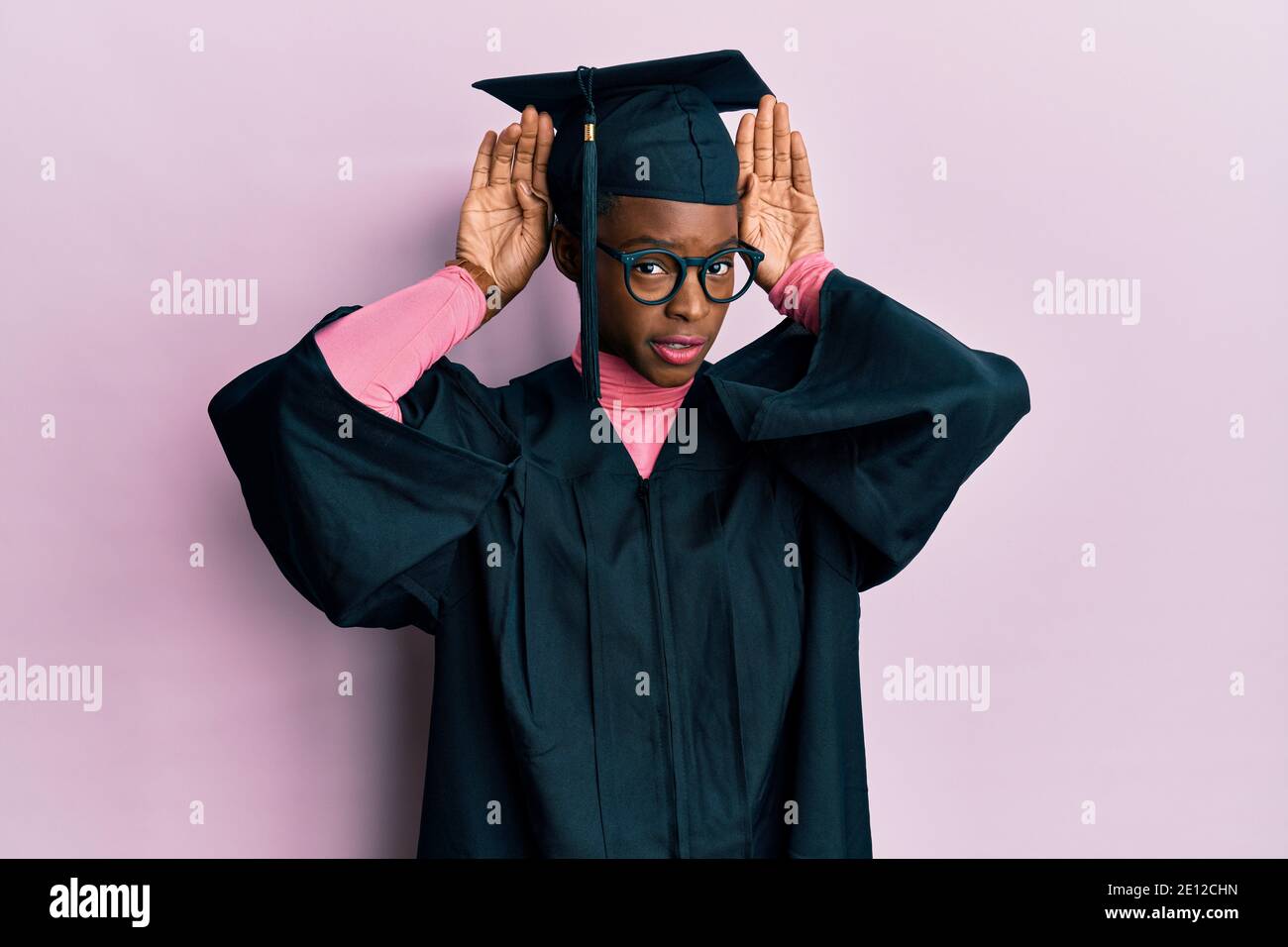 Young african american girl wearing graduation cap and ceremony robe ...