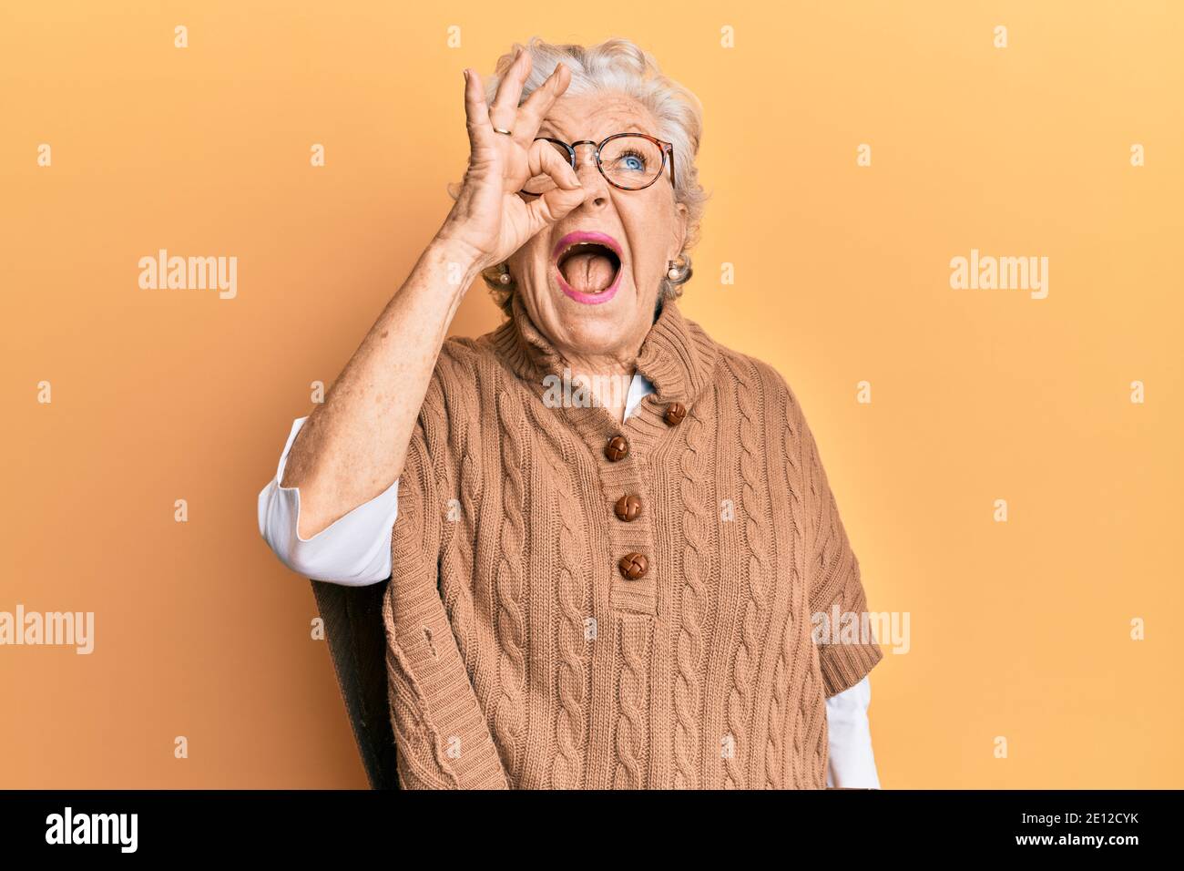 Senior grey-haired woman doing ok positive gesture on eye angry and mad ...