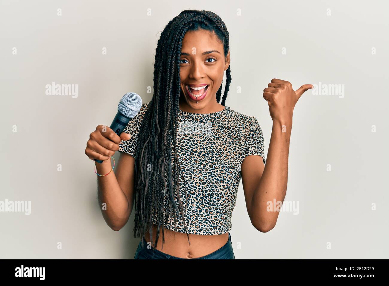 African american woman singing song using microphone pointing thumb up ...