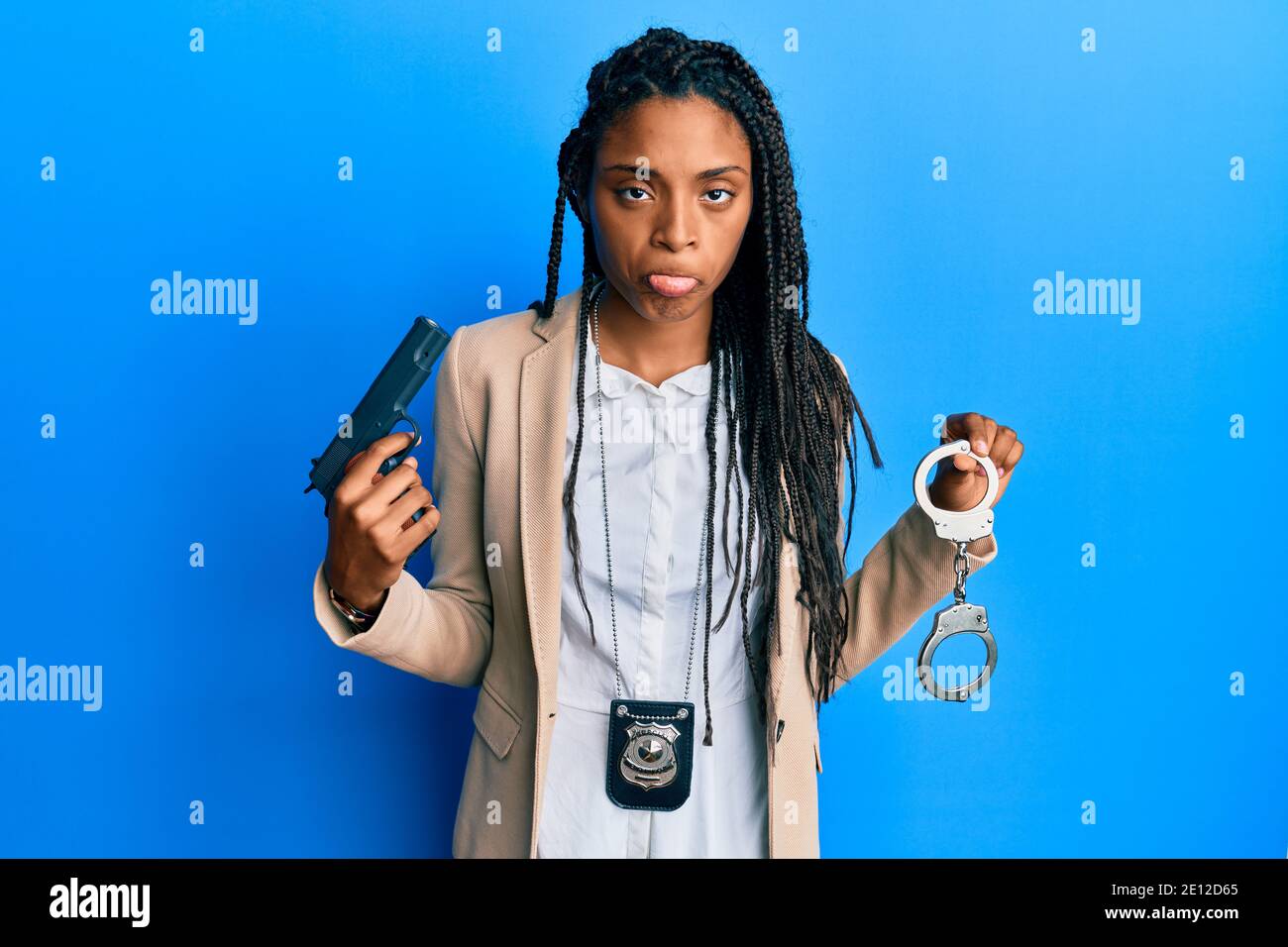 African american police woman holding gun and handcuffs depressed and ...