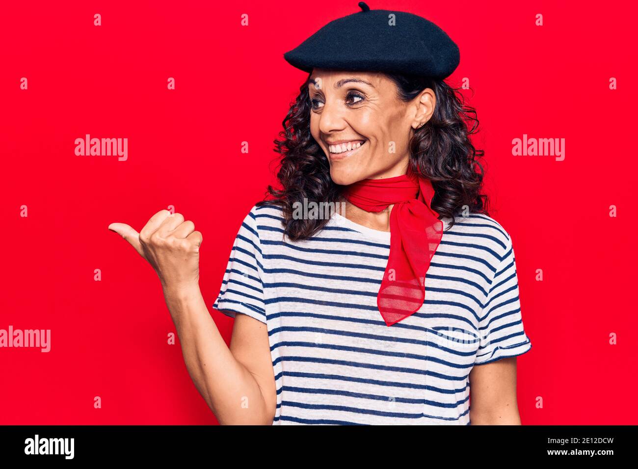 Middle age beautiful woman wearing french beret pointing thumb up to ...