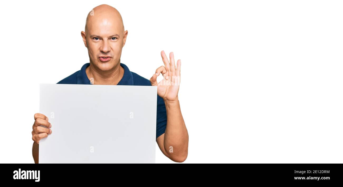 Middle age bald man holding blank empty banner doing ok sign with ...