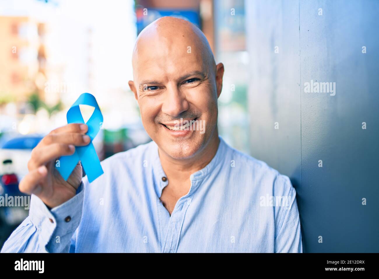 Middle age bald man smiling happy holding blue prostate cancer ribbon ...