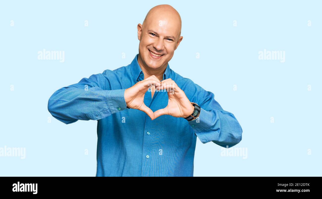 Middle age bald man wearing casual clothes smiling in love doing heart ...