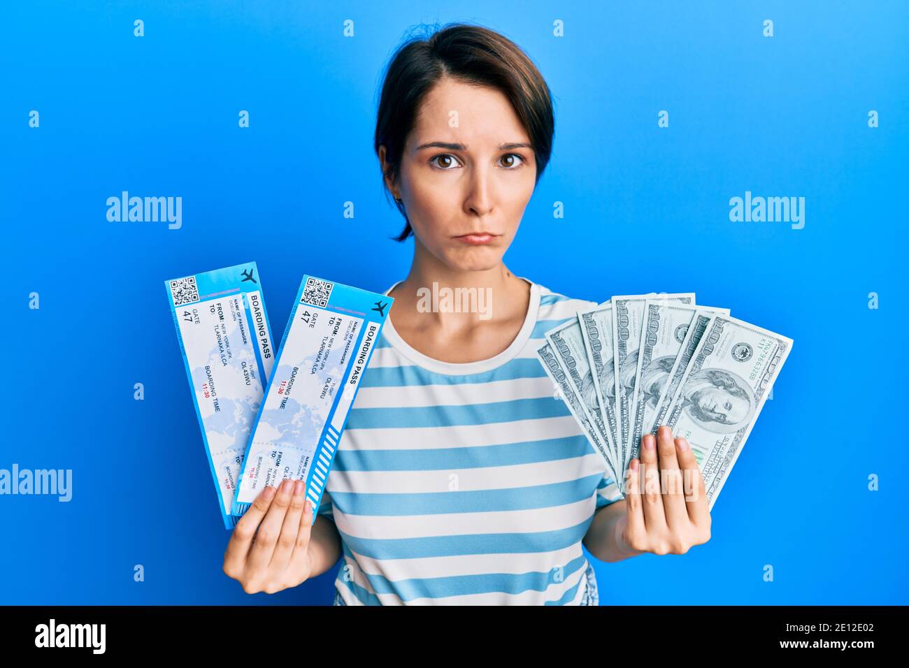 Young brunette woman with short hair holding boarding pass and dollars ...