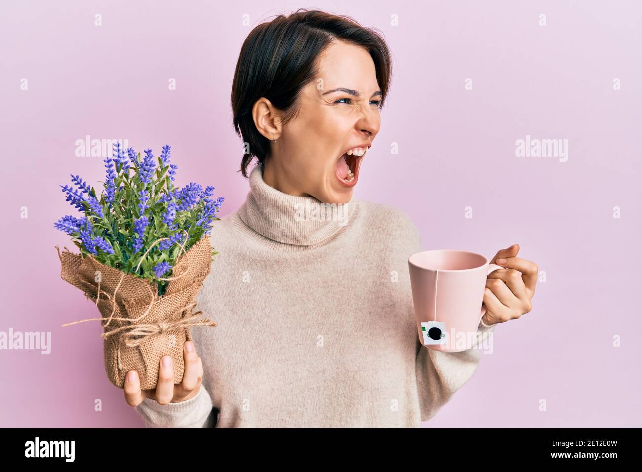 Young brunette woman with short hair drinking a cup of infused lavender ...