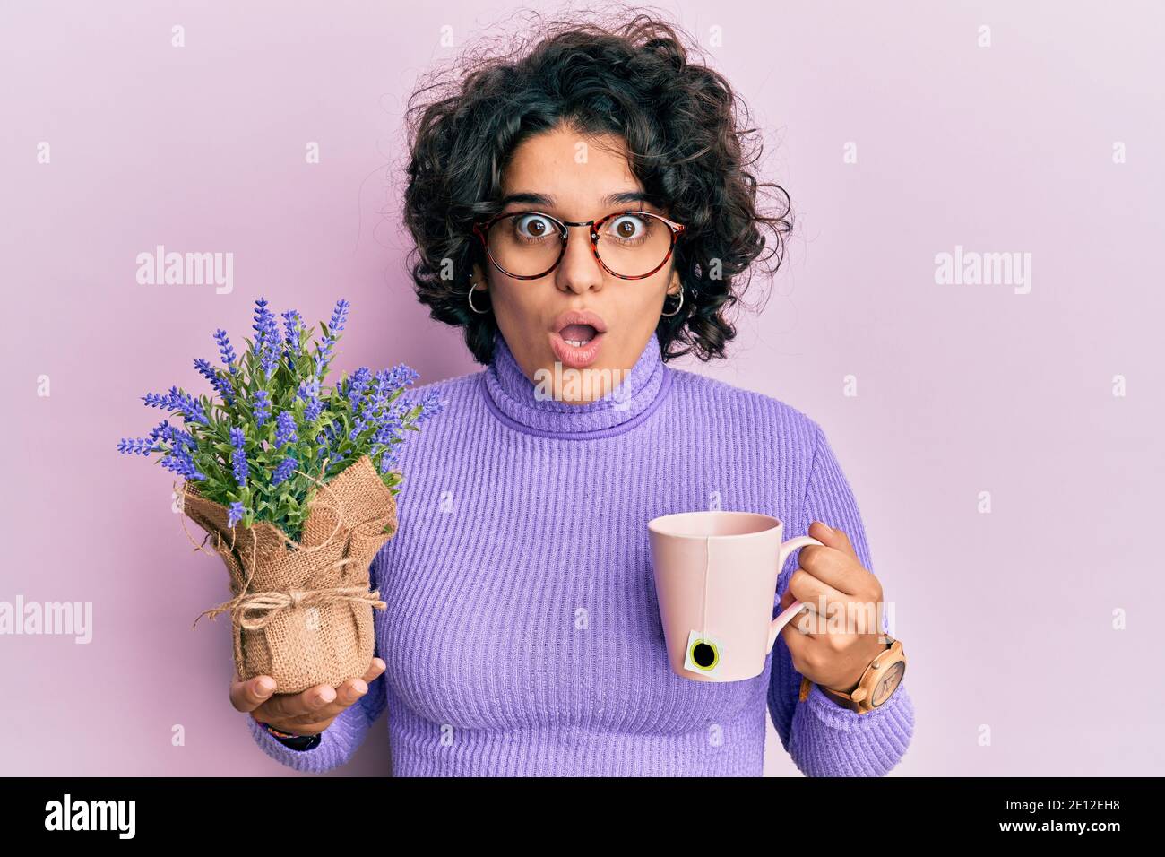 Young hispanic woman with curly hair drinking a cup of infused lavender ...