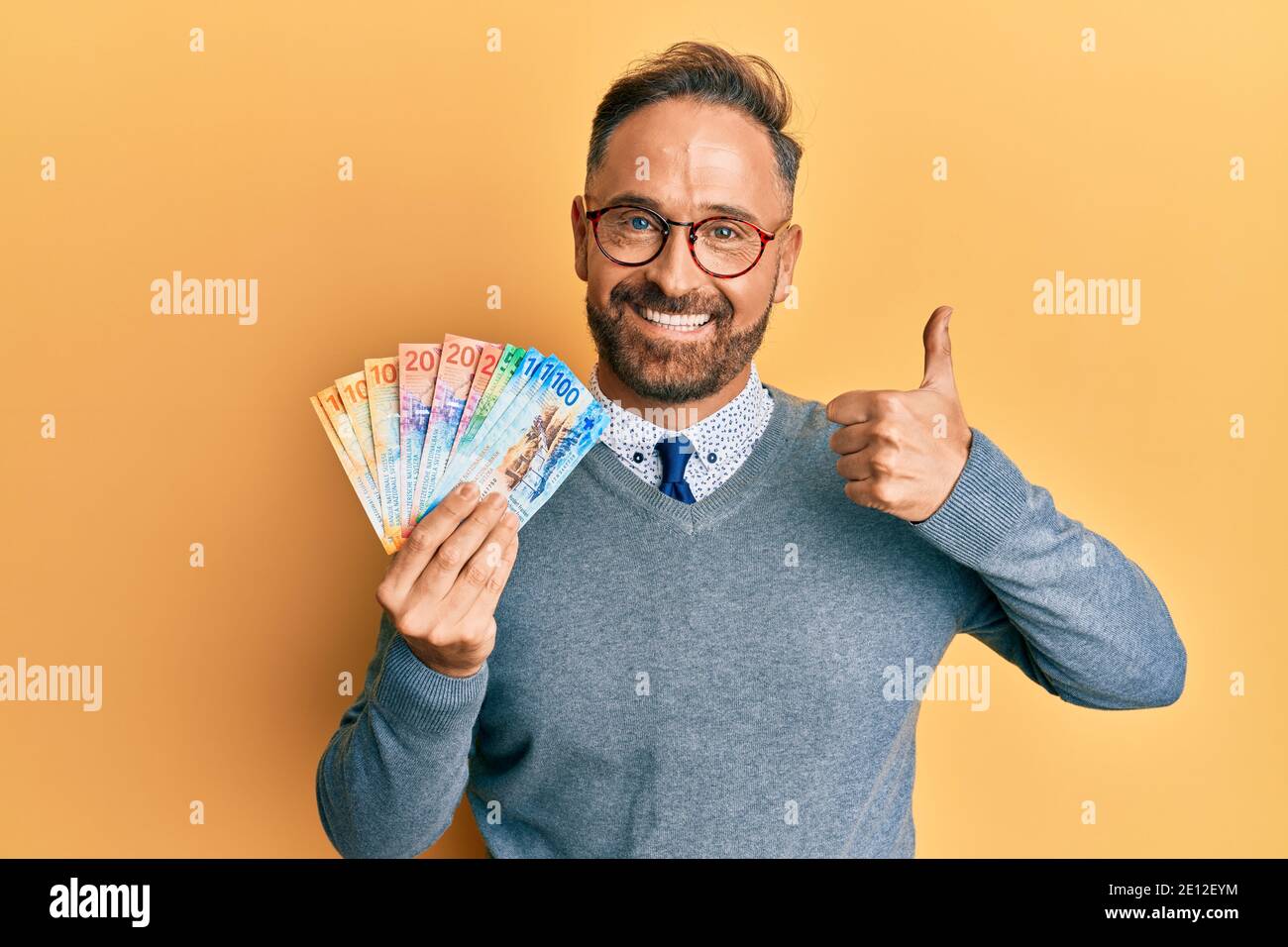 Handsome middle age man holding swiss franc banknotes smiling happy and ...