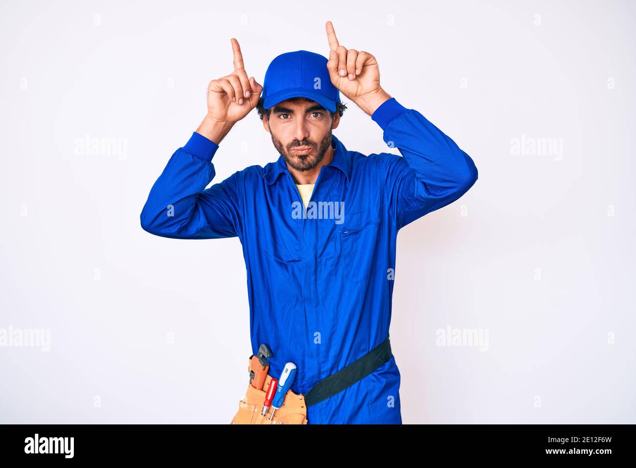 Handsome young man with curly hair and bear weaing handyman uniform ...