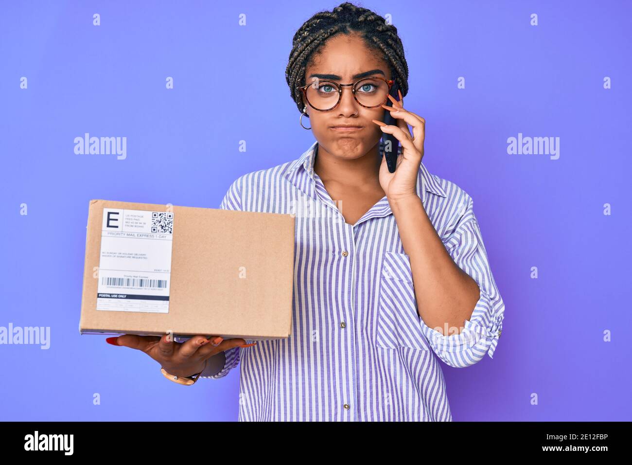 Young african american woman with braids holding delivery box calling ...