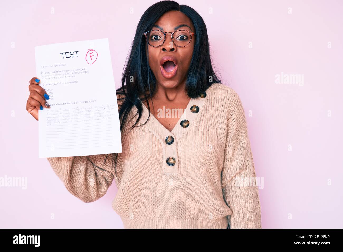 Young african american woman showing a failed exam scared and amazed ...