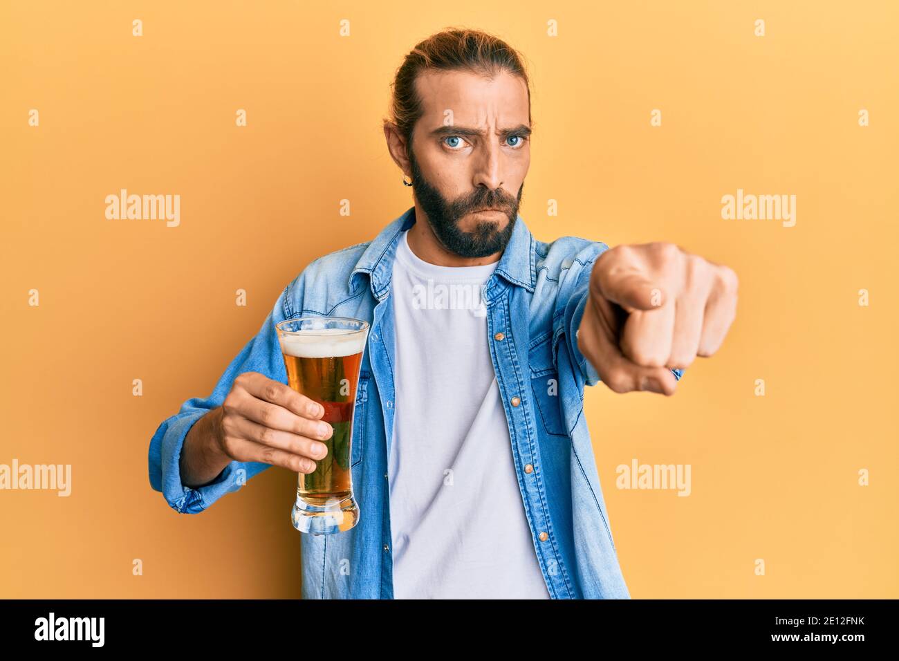 Attractive man with long hair and beard drinking a pint of beer ...