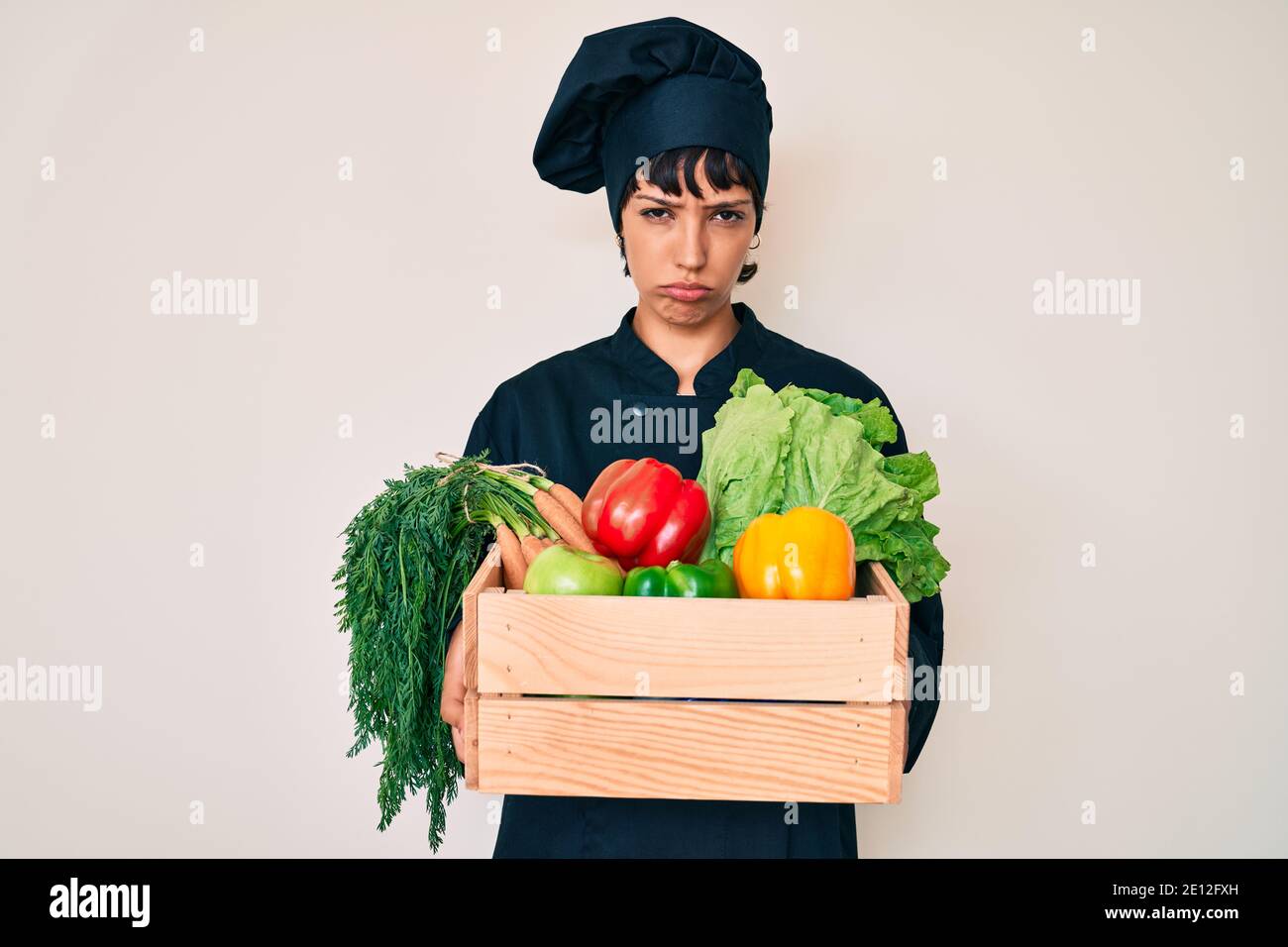 Beautiful brunettte woman chef holding fresh veggetables depressed and ...
