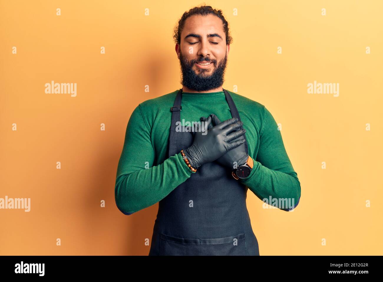 Young arab man wearing barber apron smiling with hands on chest with ...