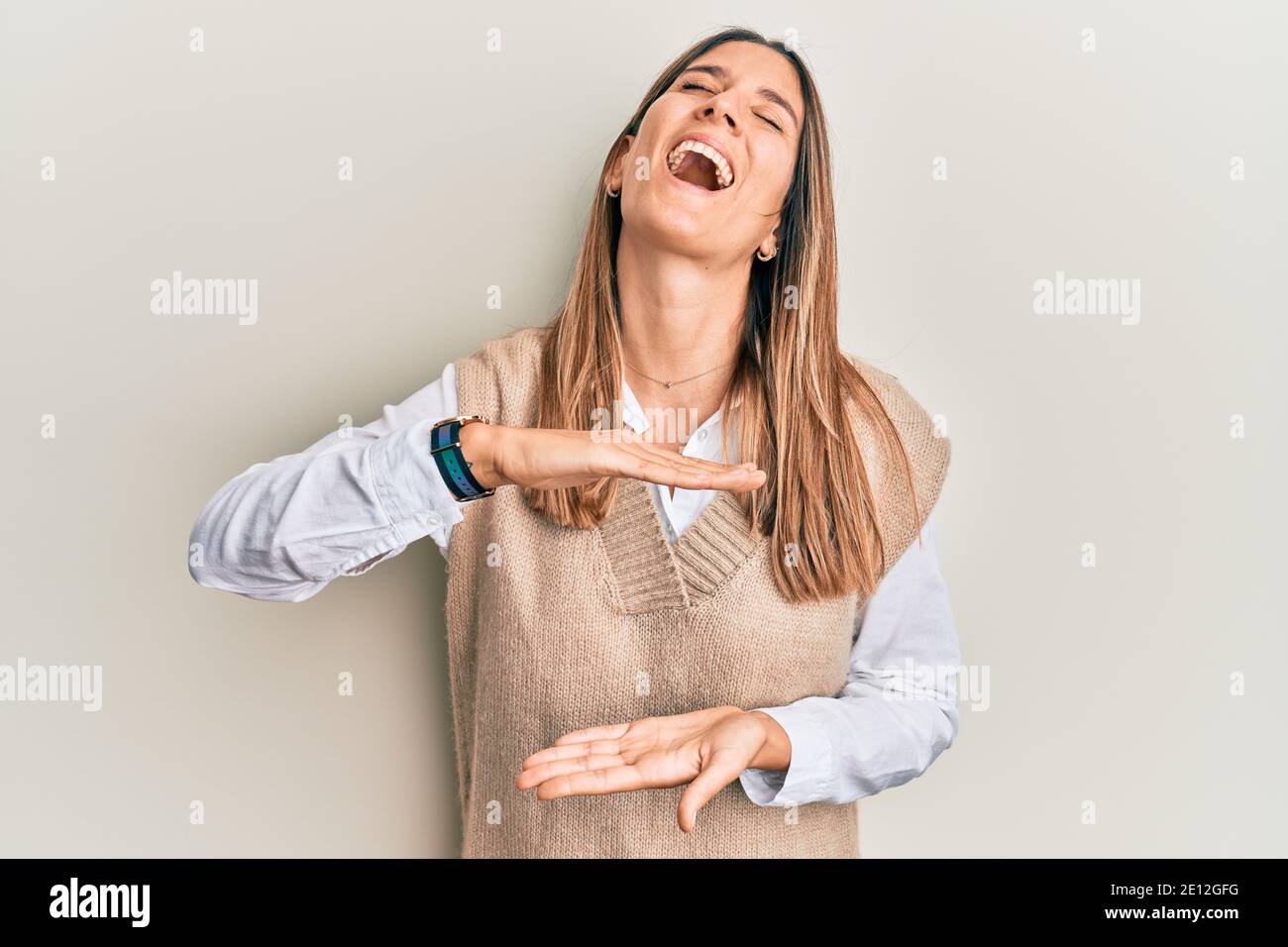 Brunette young woman doing size gesture holding invisible object ...