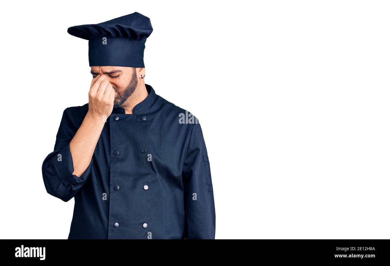 Young hispanic man wearing cooker uniform tired rubbing nose and eyes ...