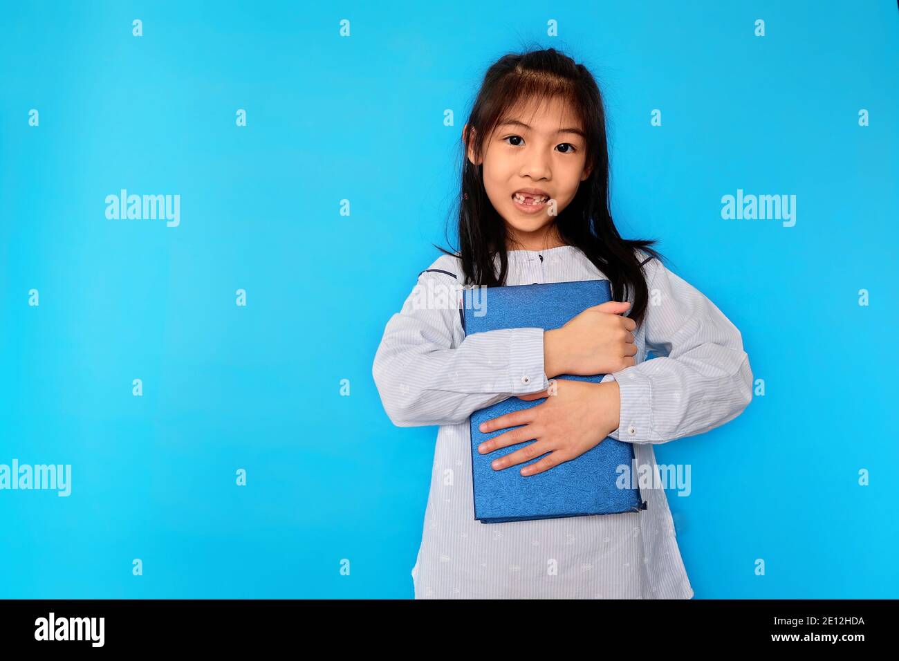A cute young Asian girl is feeling happy after receiving her new book ...