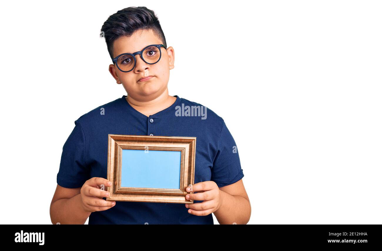 Little boy kid holding empty frame thinking attitude and sober ...