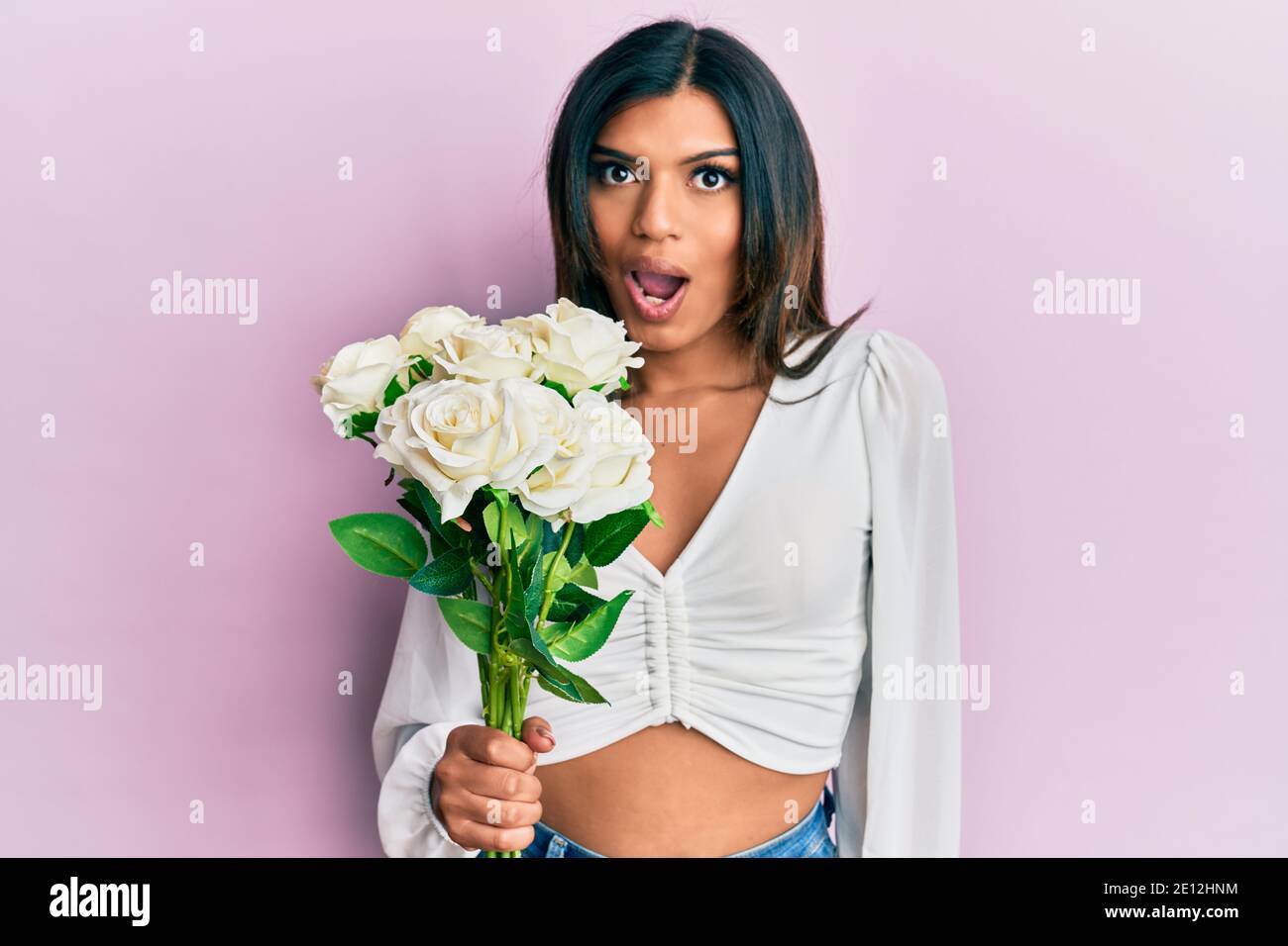 Young latin transsexual transgender woman holding flowers scared and ...