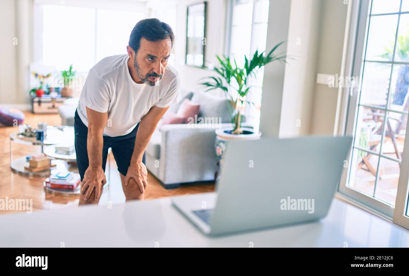 Middle age man with beard training and stretching doing exercise at ...