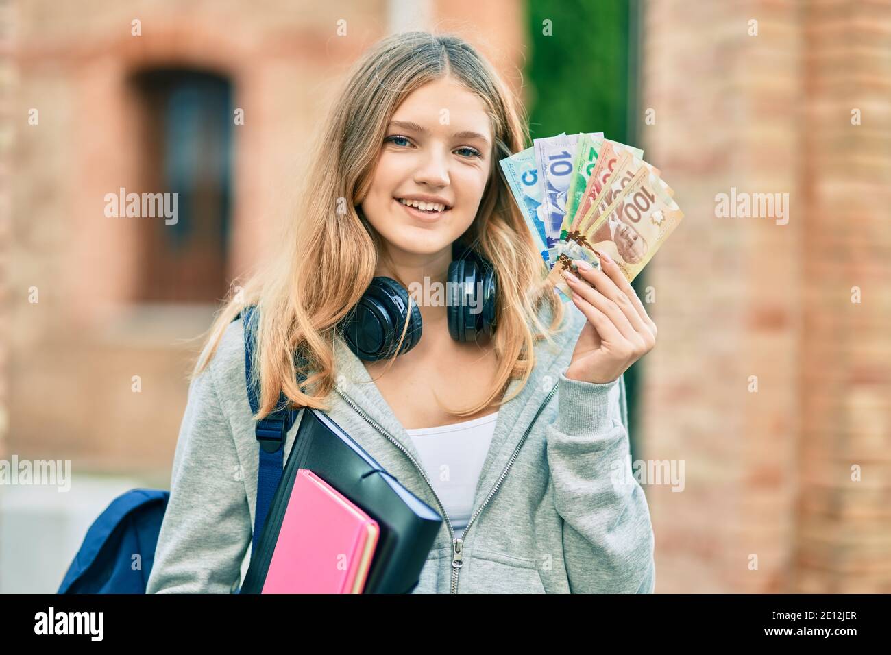 Beautiful caucasian student teenager using headphones holding canadian ...