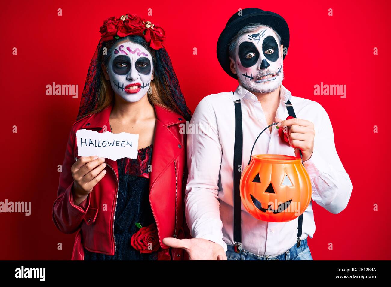 Couple wearing day of the dead costume holding pumpking and halloween ...