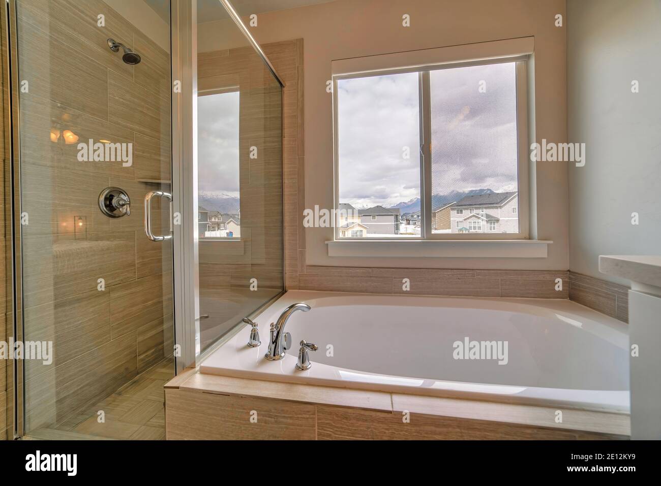 Shower stall with glass wall and door beside built in bathtub inside ...