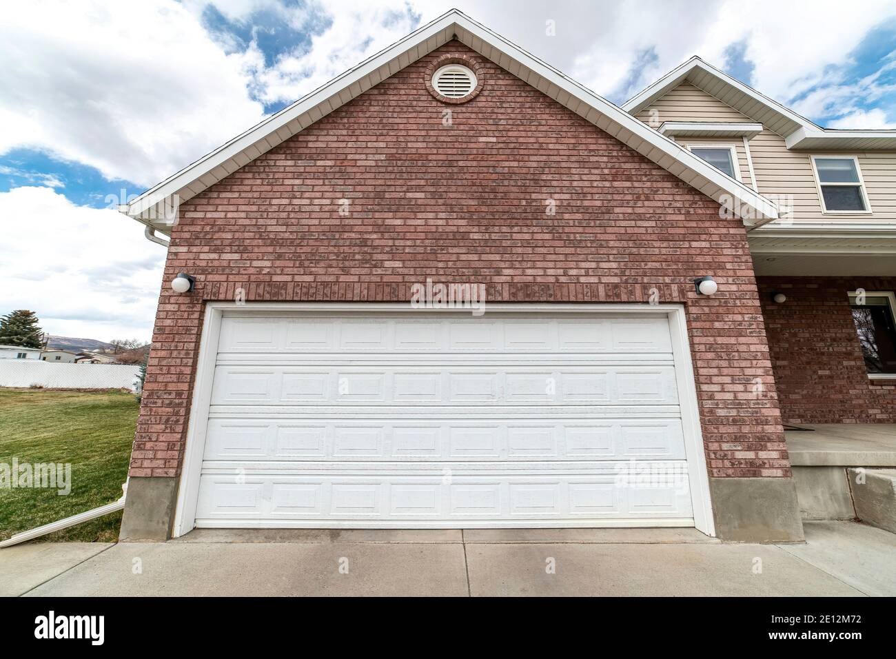 Front view of attached garage of home with white door brick wall and ...