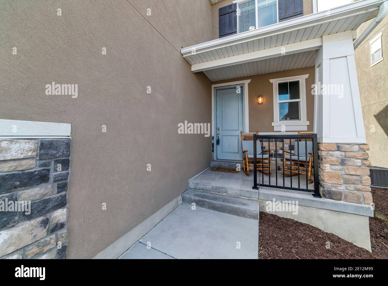 Home facade with rocking chairs at the small front porch with railing ...