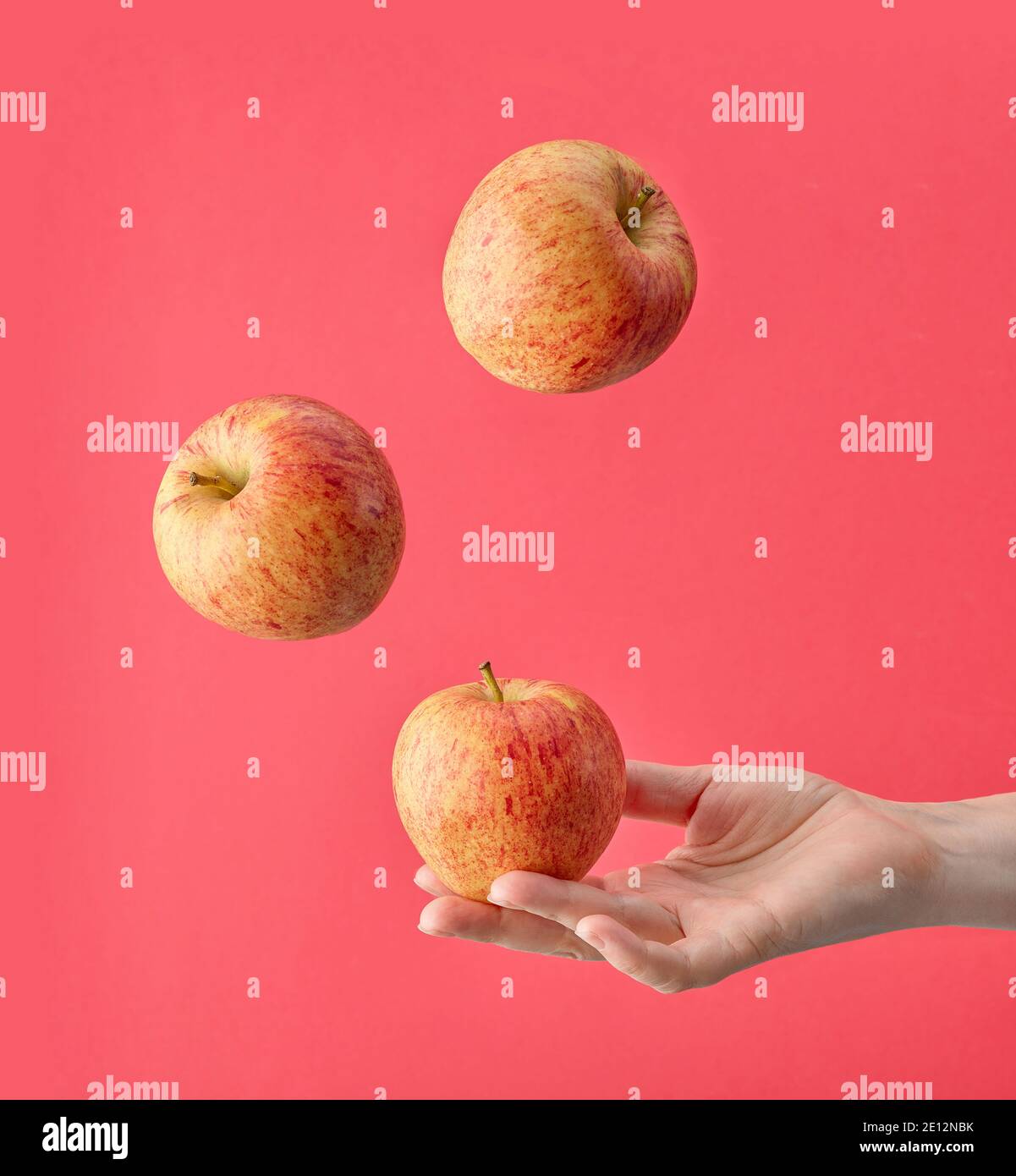 fresh apple in human hand and some levitating apples isolated on pink ...