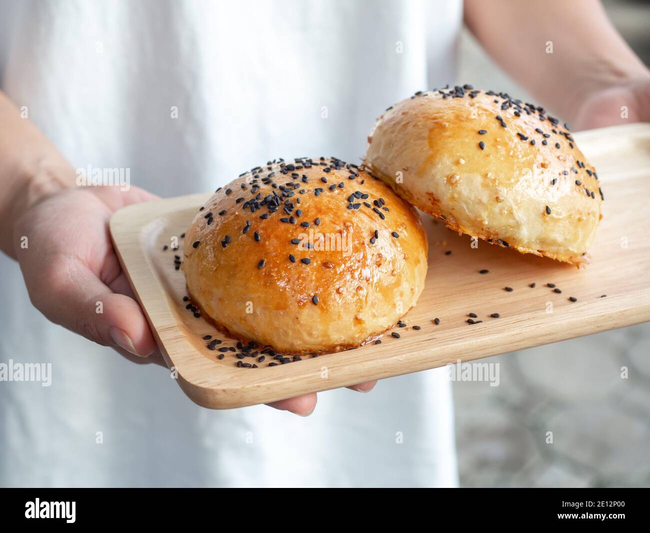 Two fresh homemade burger buns topped with black sesame seed on small ...