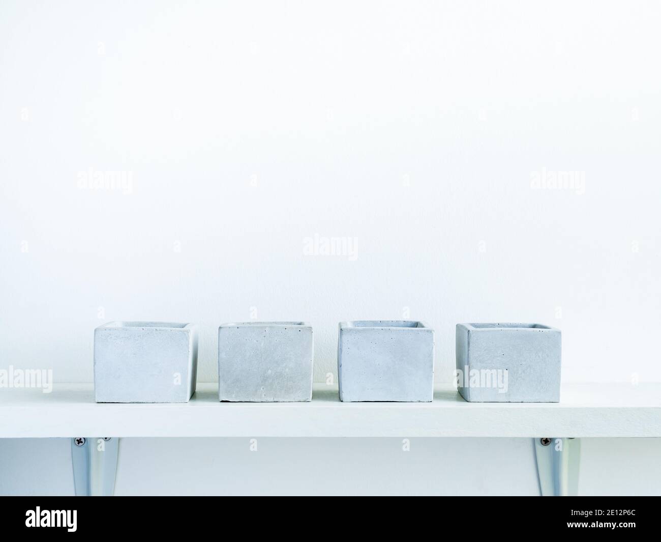 Four of empty modern geometric concrete planters on white wood shelf ...