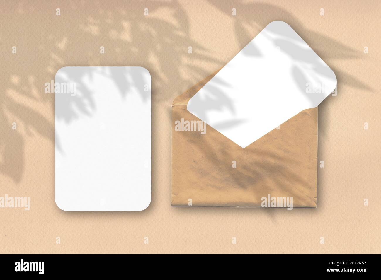 Envelope with 2 sheets of white textured paper on the pastel-beige wall ...