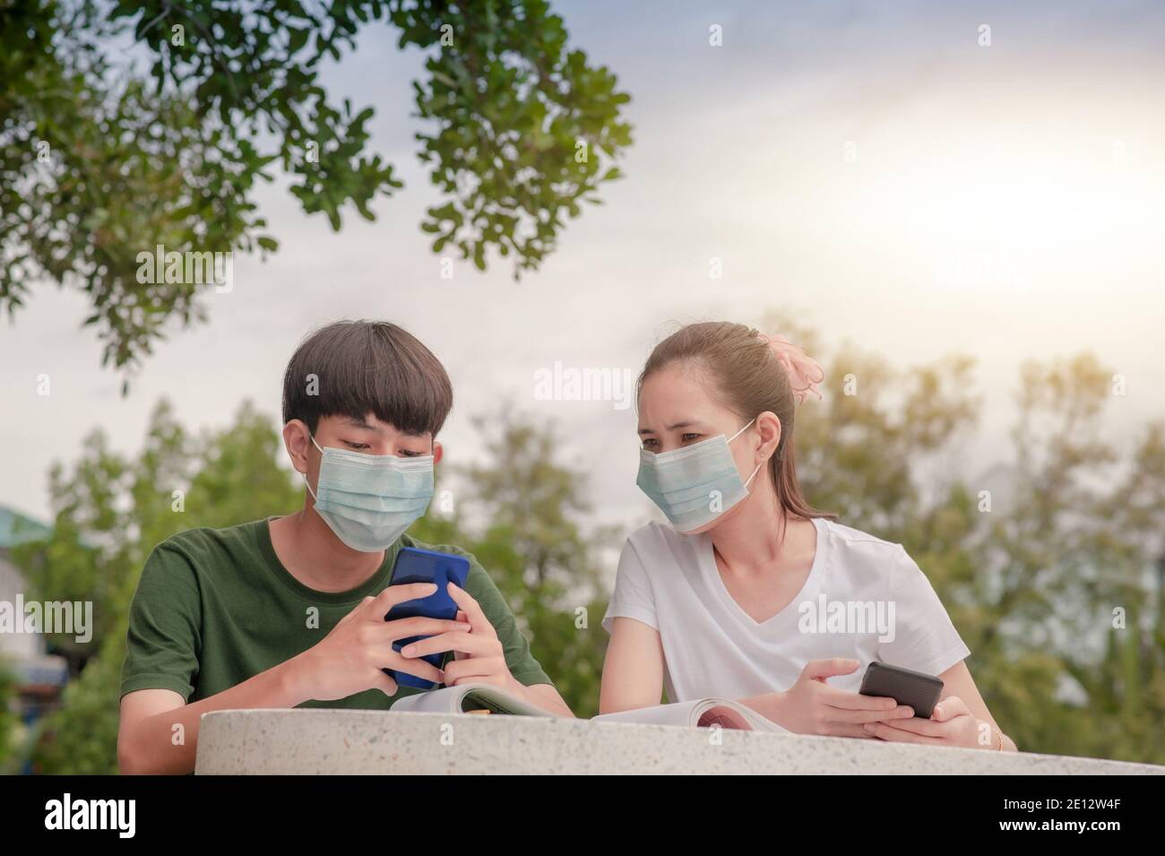 Boy and Girl in face mask new normal using mobile smart phone keep ...
