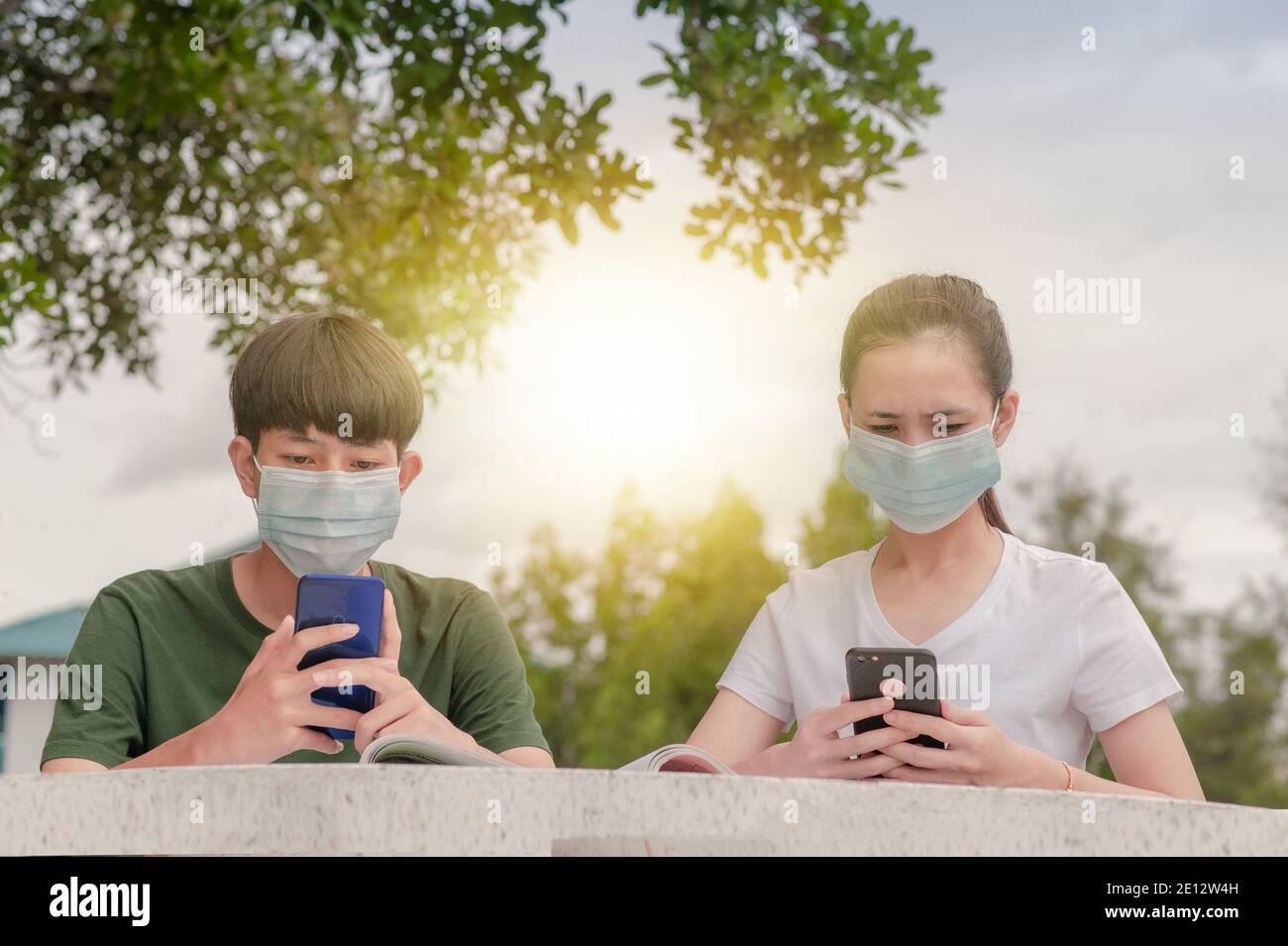 Boy and Girl in face mask new normal using mobile smart phone keep ...