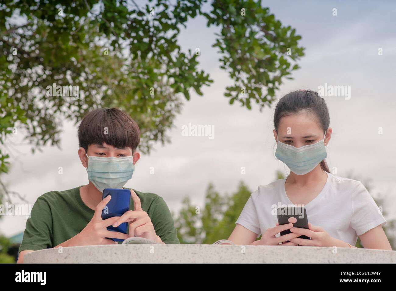 Boy and Girl in face mask new normal using mobile smart phone keep ...