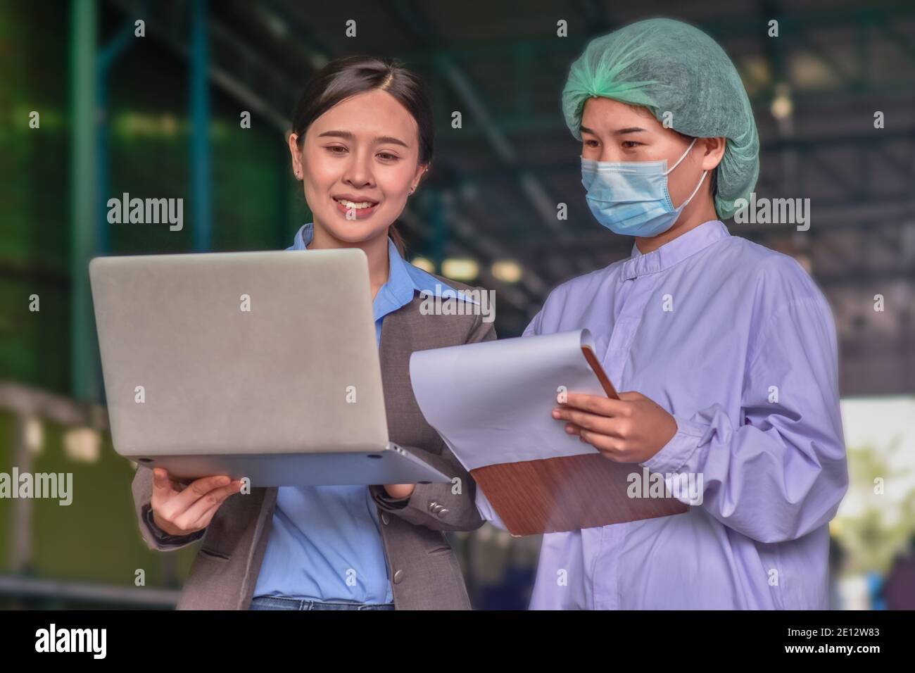 Business women manager talking with operator by computer in factory ...