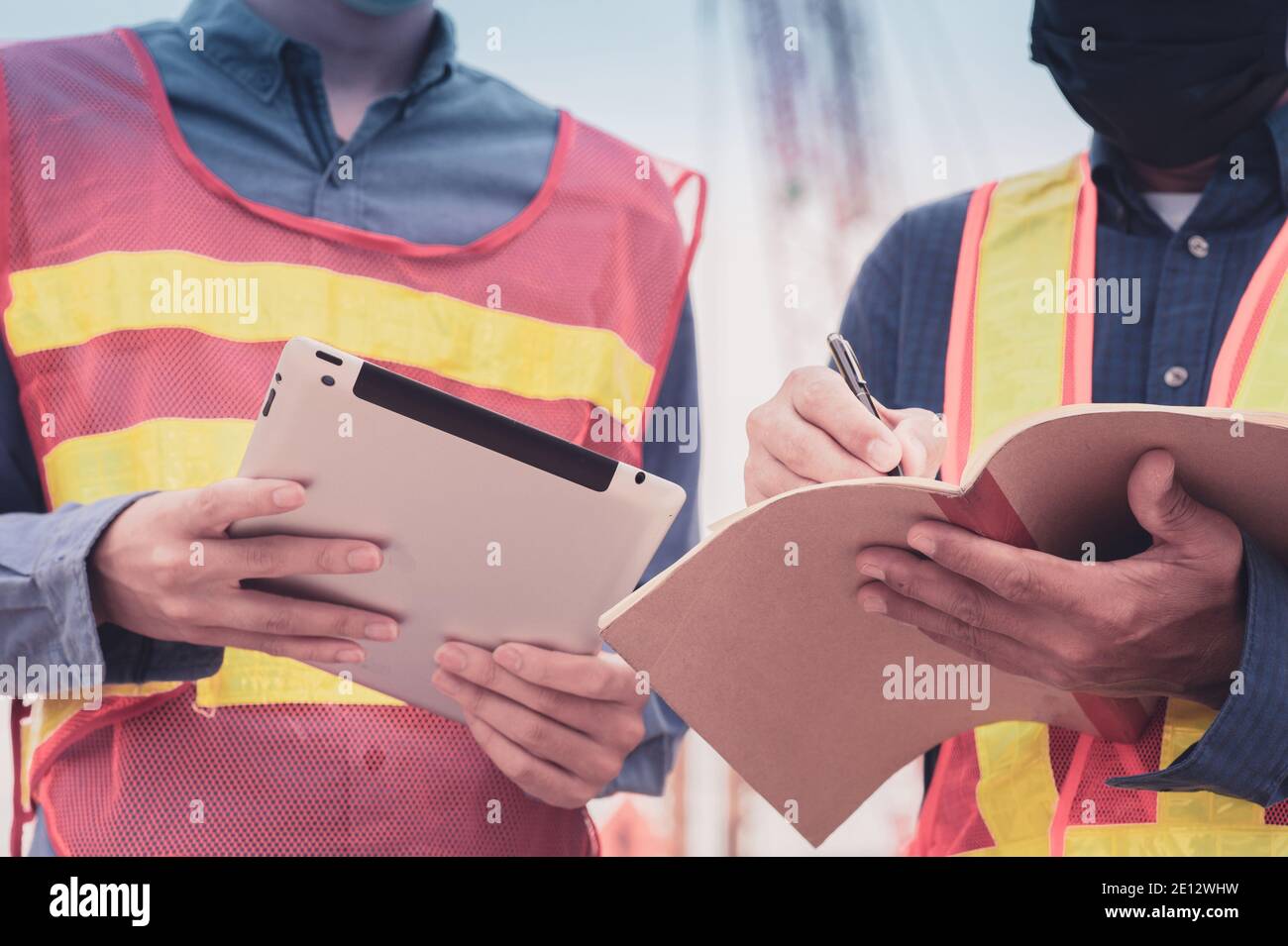 Two Engineer wear face mask write on book working on site construction ...
