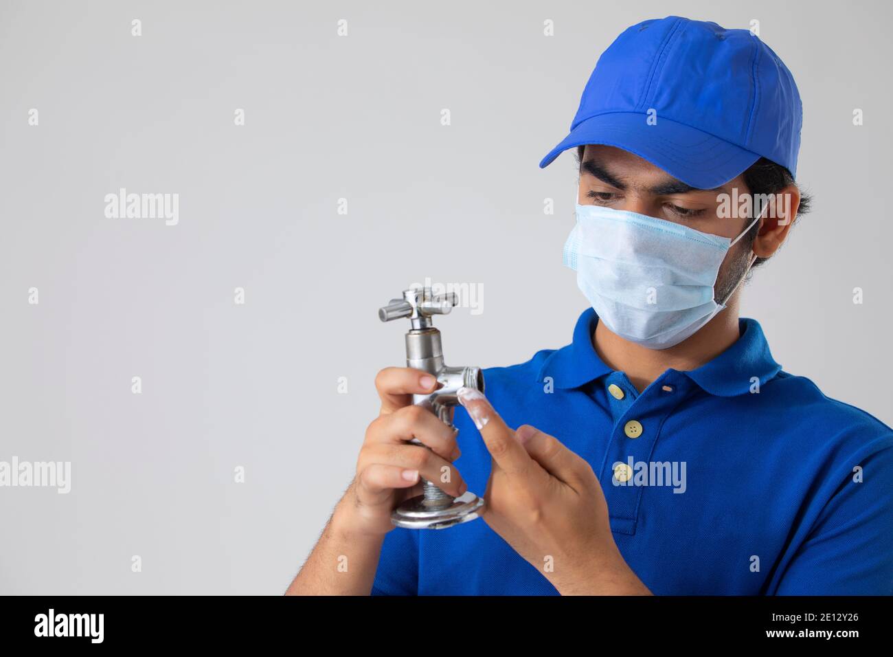 A PLUMBER WEARING FACE MASK REPAIRING A BROKEN TAP Stock Photo - Alamy